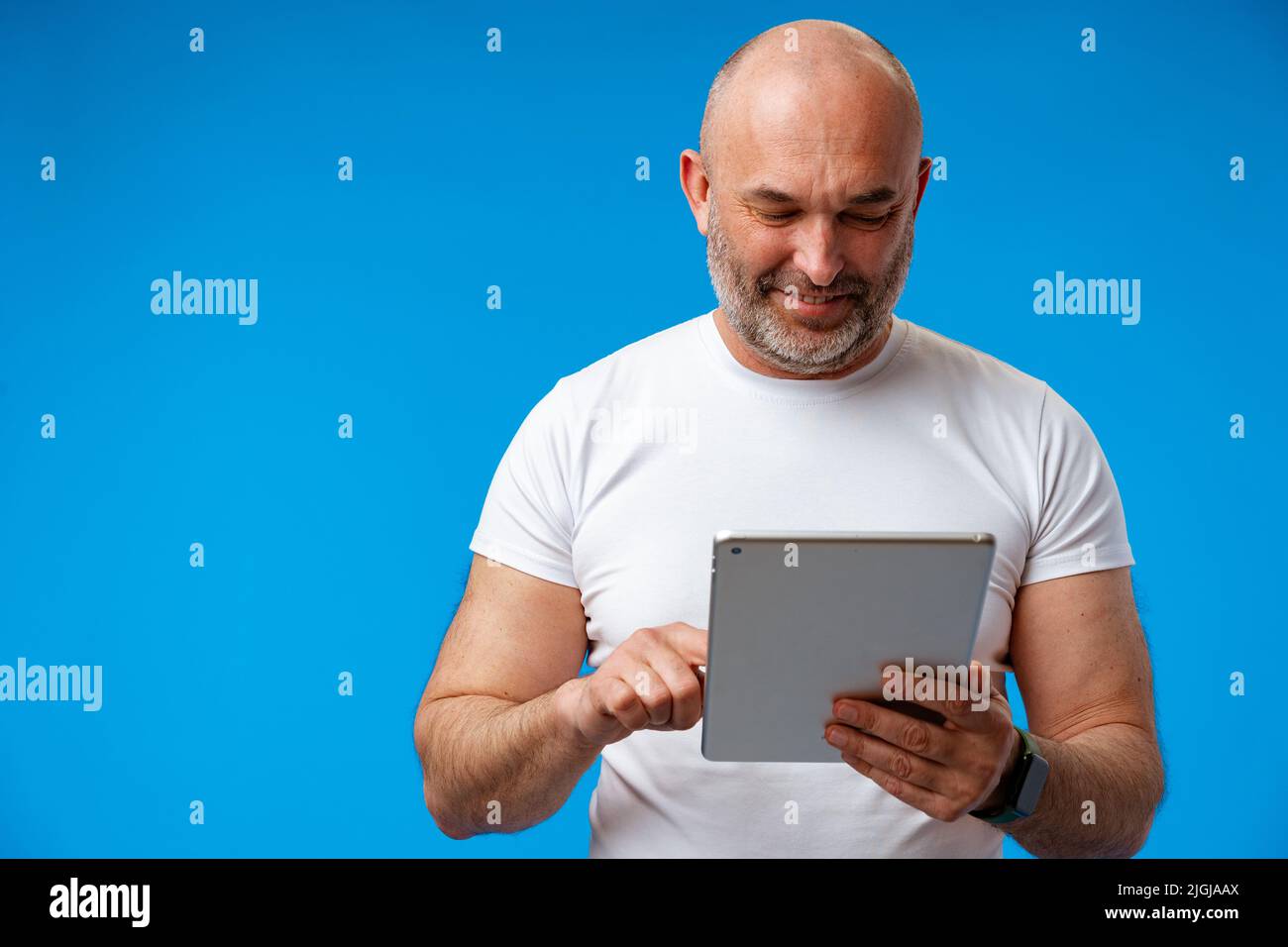 Handsome middle age man with digital tablet against blue background ...