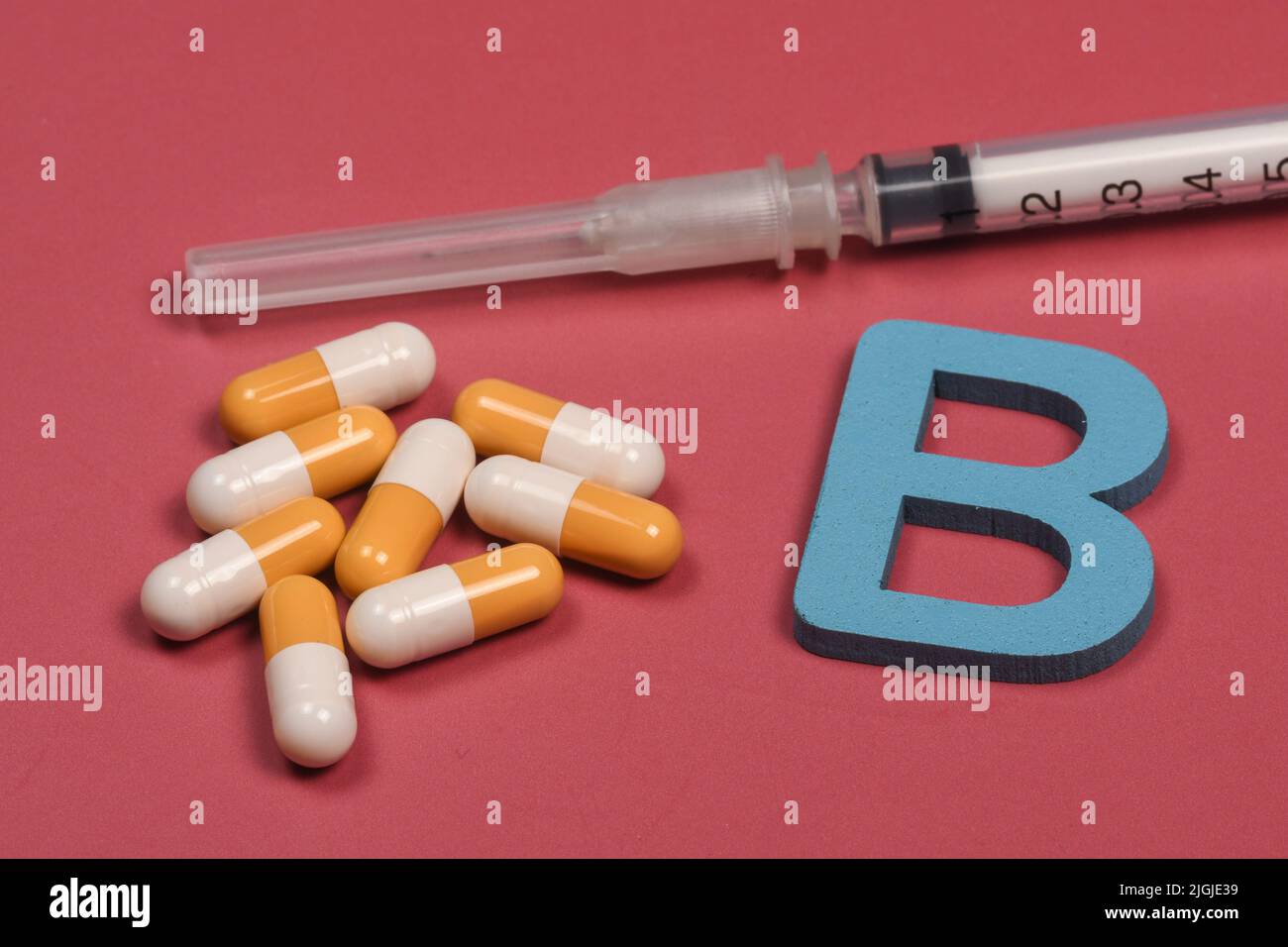 yellow and white medicine capsules on red background and insulin pen ...
