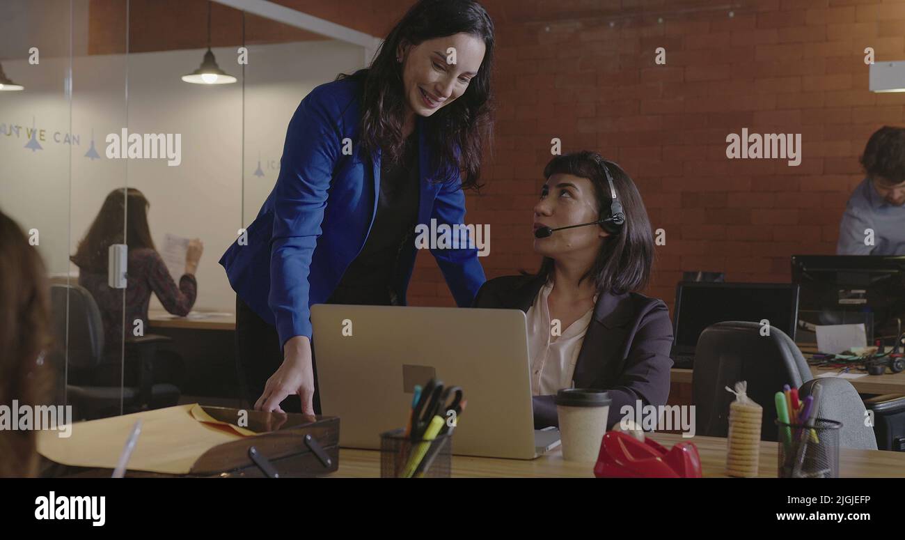 Executive female leader chief helping younger employer wearing headset ...