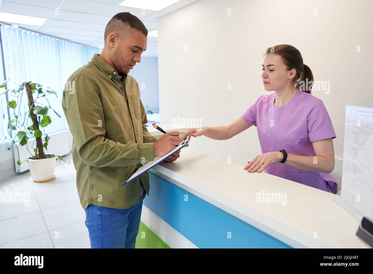 Man filling out medical patient form in clinic Stock Photo - Alamy