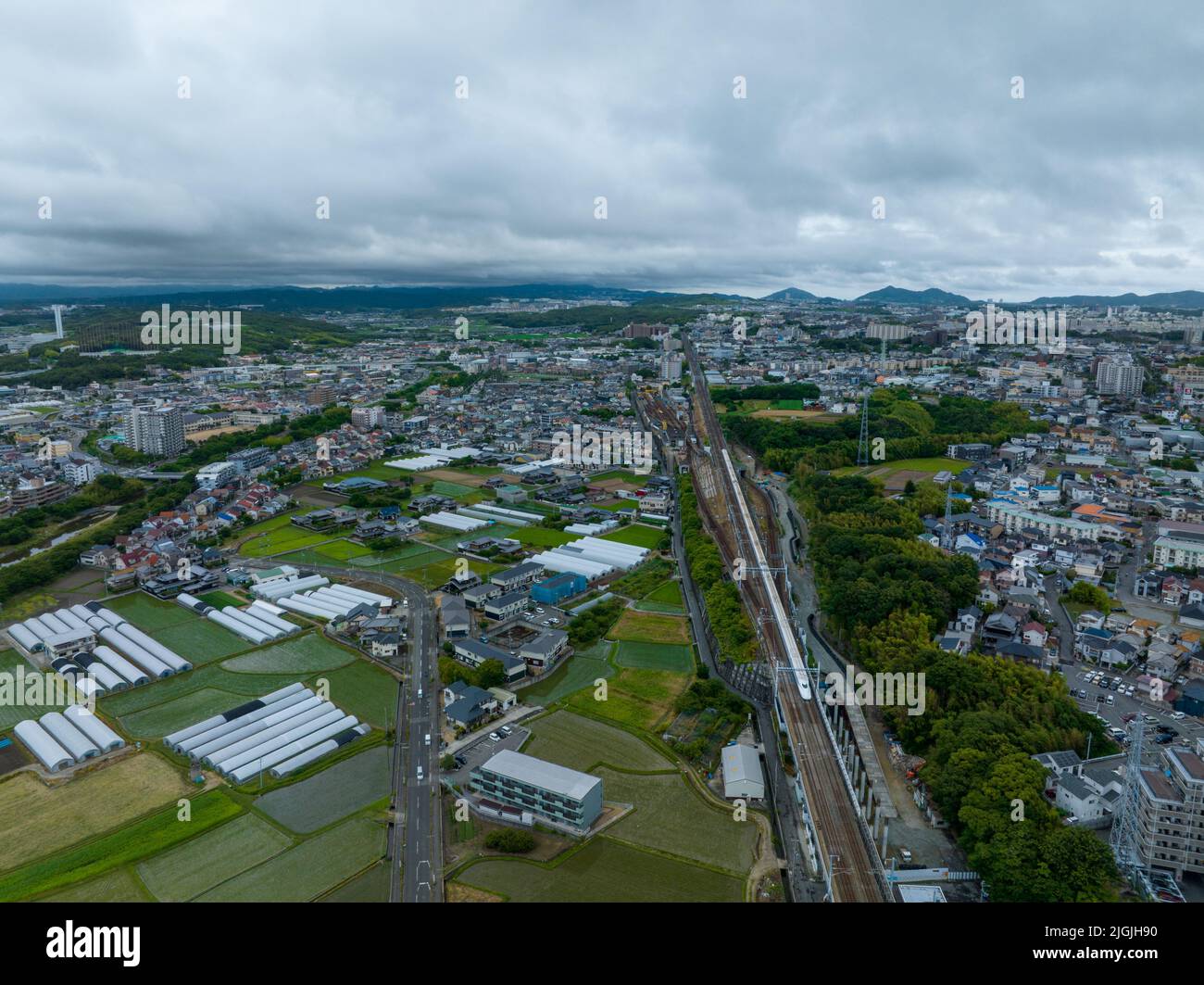 Looking down on bullet train between rice fields and suburban sprawl ...