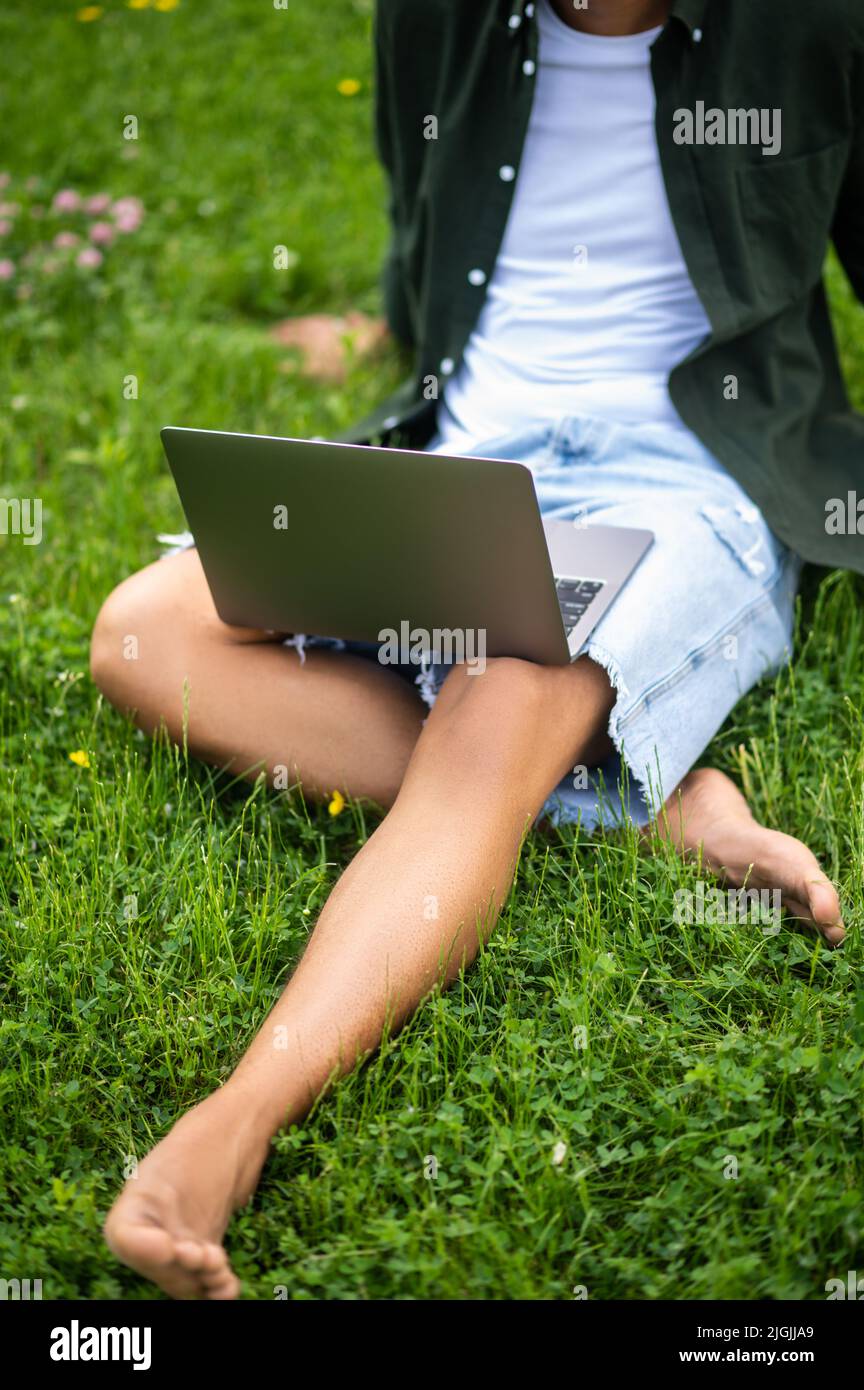 Barefoot man on grass with laptop without face Stock Photo - Alamy