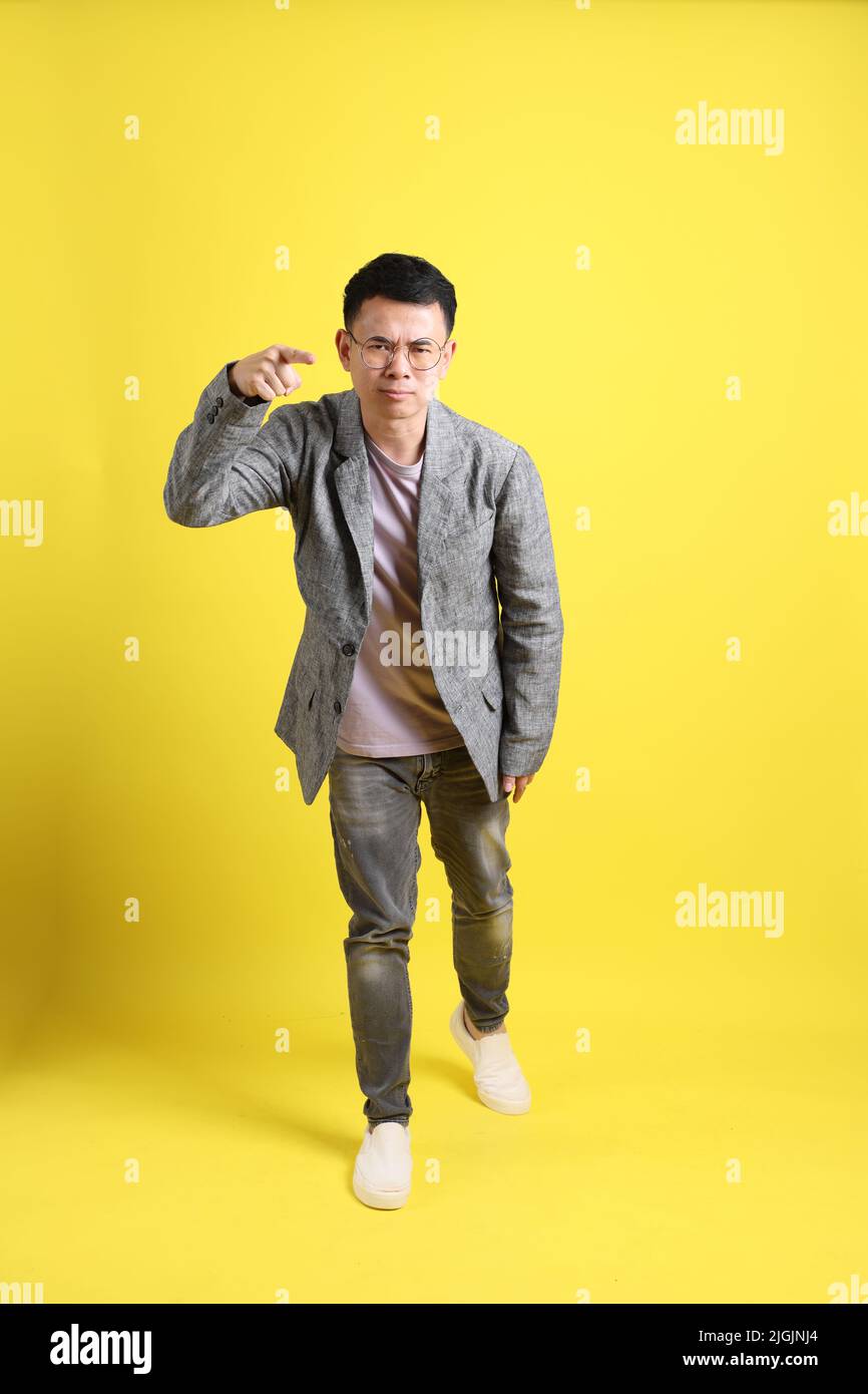 The Asian LGBTQ man with grey blazer standing on the yellow background ...