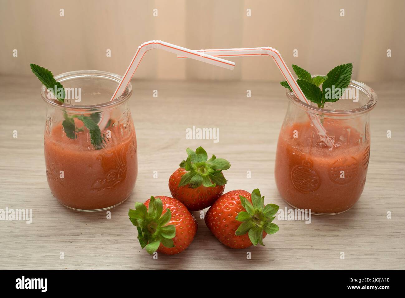 Two strawberry milkshakes in a glass with straws Stock Photo - Alamy