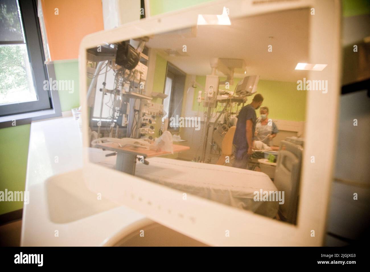 Reflection in a screen of a monitoring of a patient's room with nurses ...