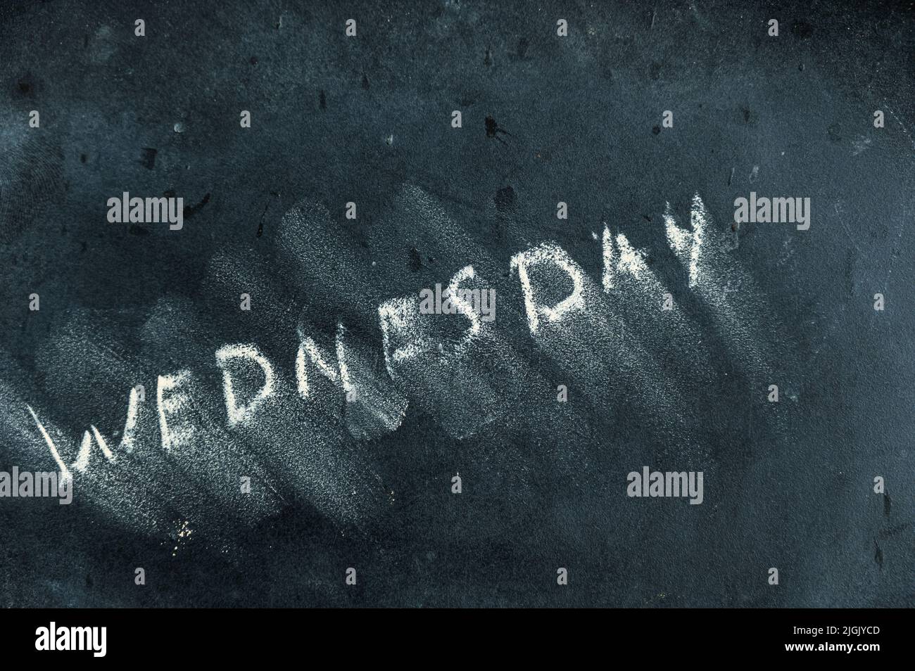 Semi-erased word WEDNESDAY on black chalkboard. Handwritten word. Fuzzy ...