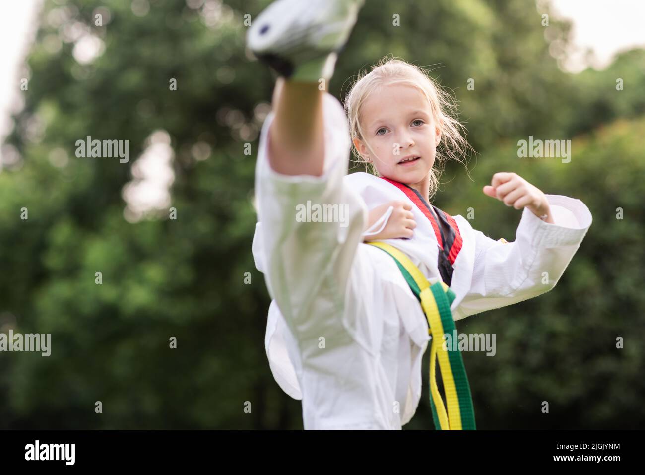 Caucasian little girl seven years old in kimono with yellow green belt ...