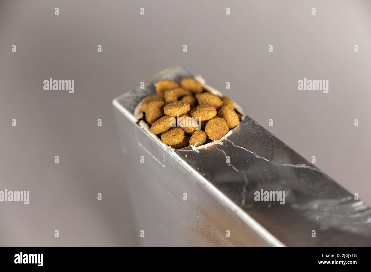 A silver rectangular box against a gray background. Pet food spilling ...