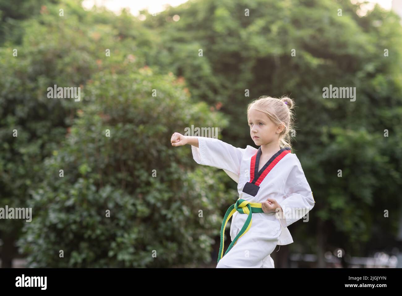 Caucasian little girl seven years old in kimono with yellow green belt ...