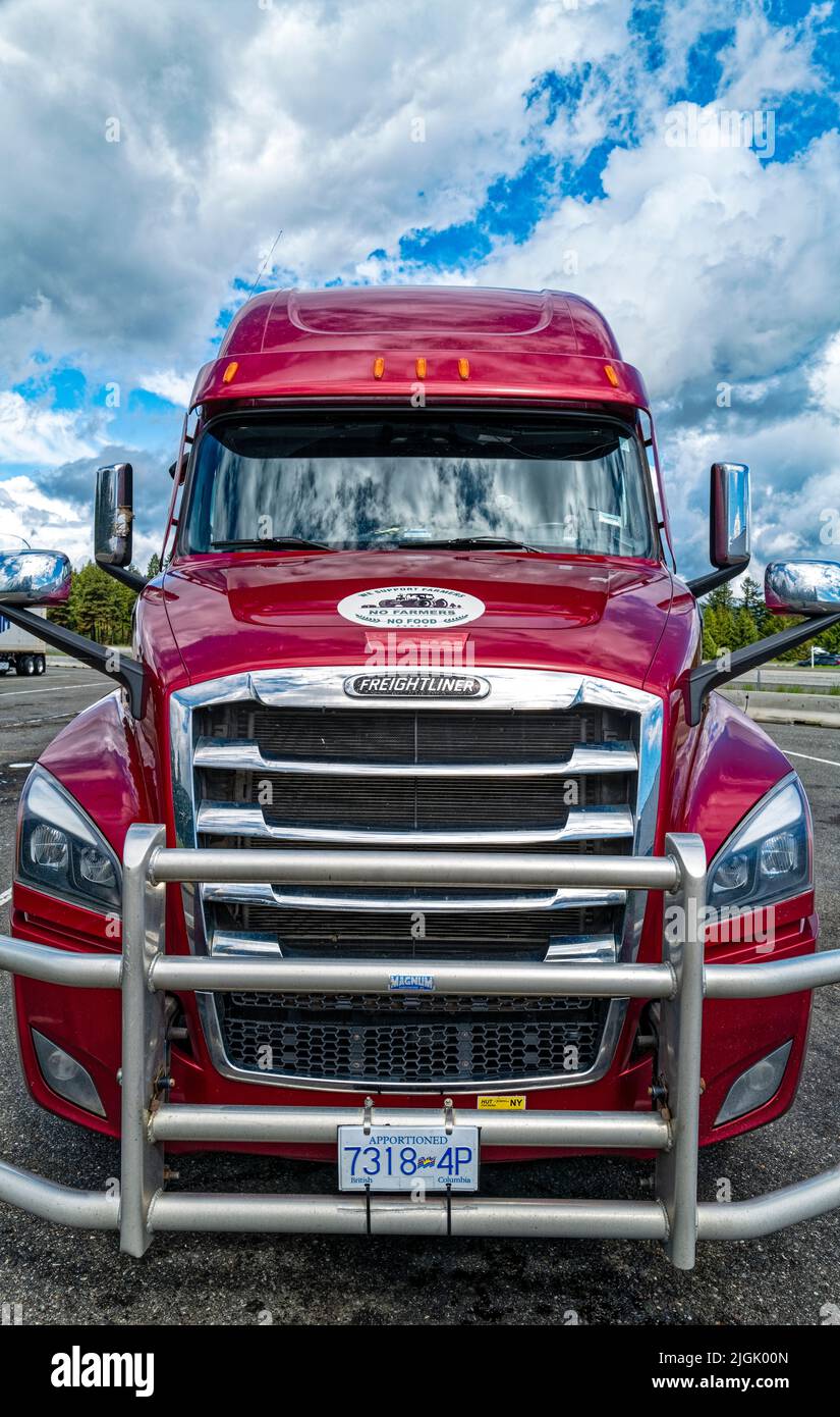 The front of a red Freightliner Cascadia semi truck parked in a rest ...