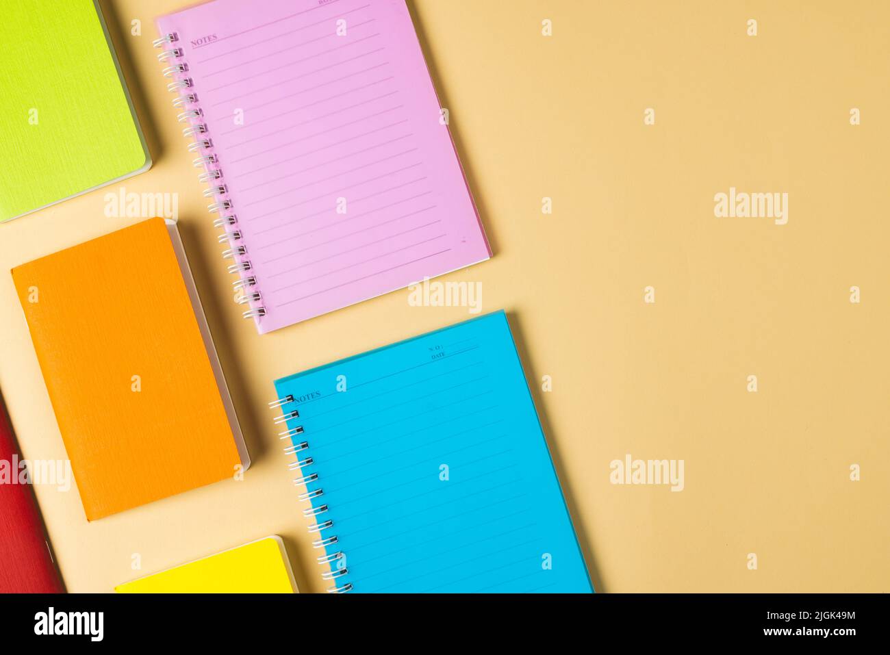 Composition of colorful notebooks lying on yellow surface with copy ...
