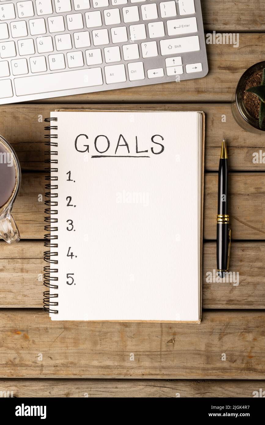 Vertical image of notebook with goals and copy space on wooden surface ...