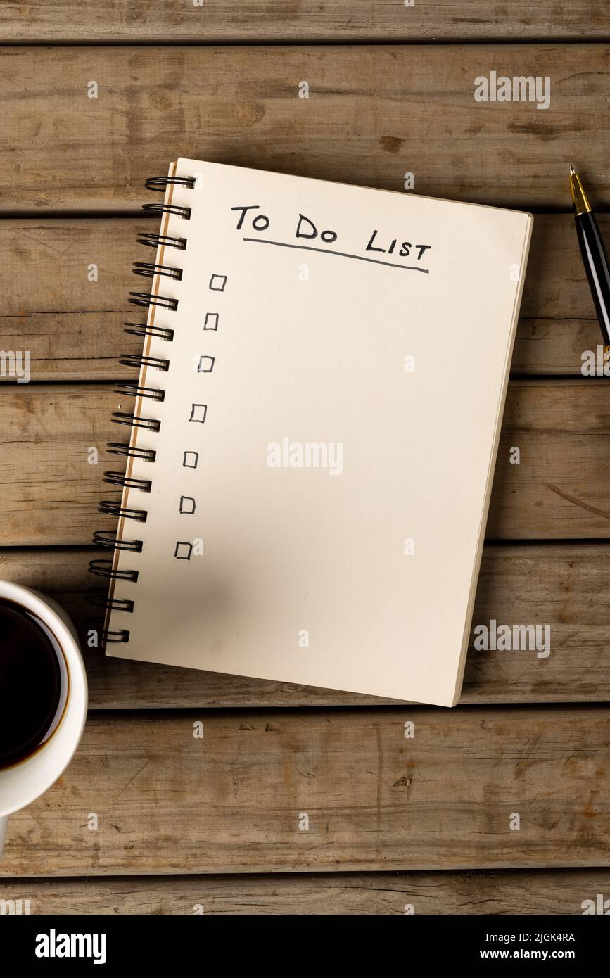 Vertical image of notebook with to do list and copy space on wooden ...