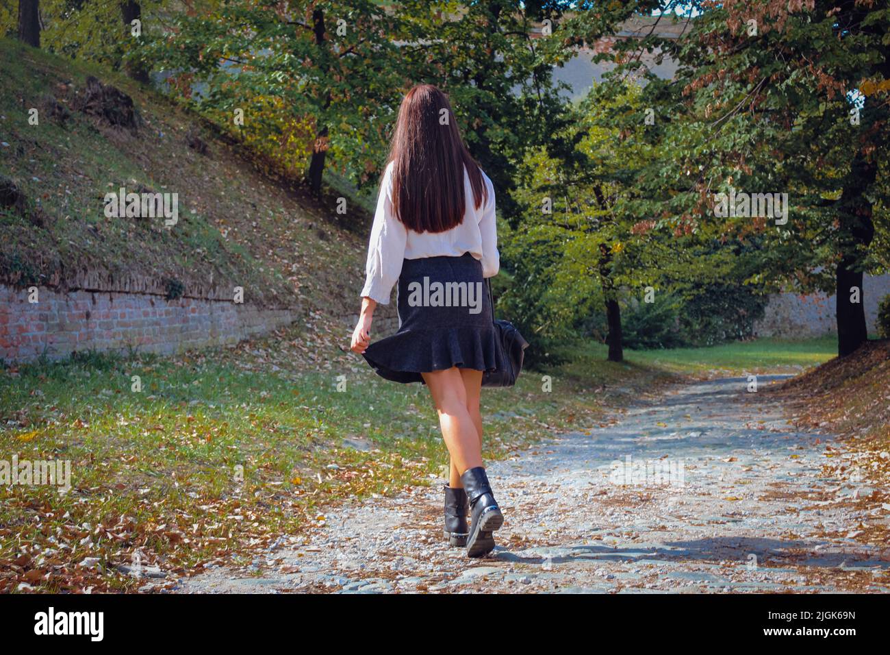 Autumn scene. Young girl with her back turned in skirt and shirt in ...
