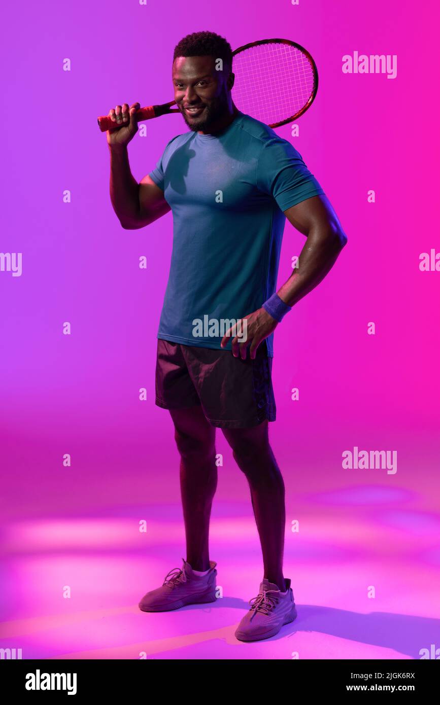 Vertical image of happy african american male tennis player in neon ...