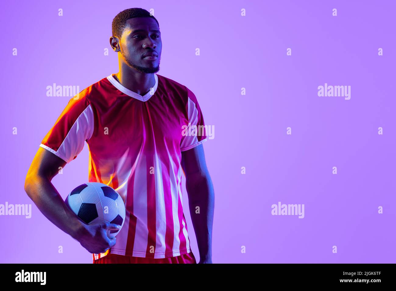 African american male soccer player with football over neon pink ...