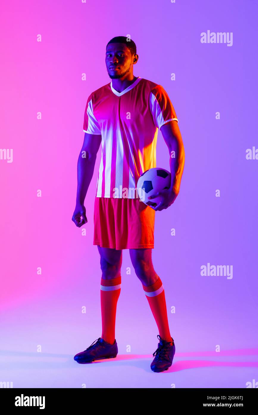 Portrait of african american male soccer player with football over neon ...