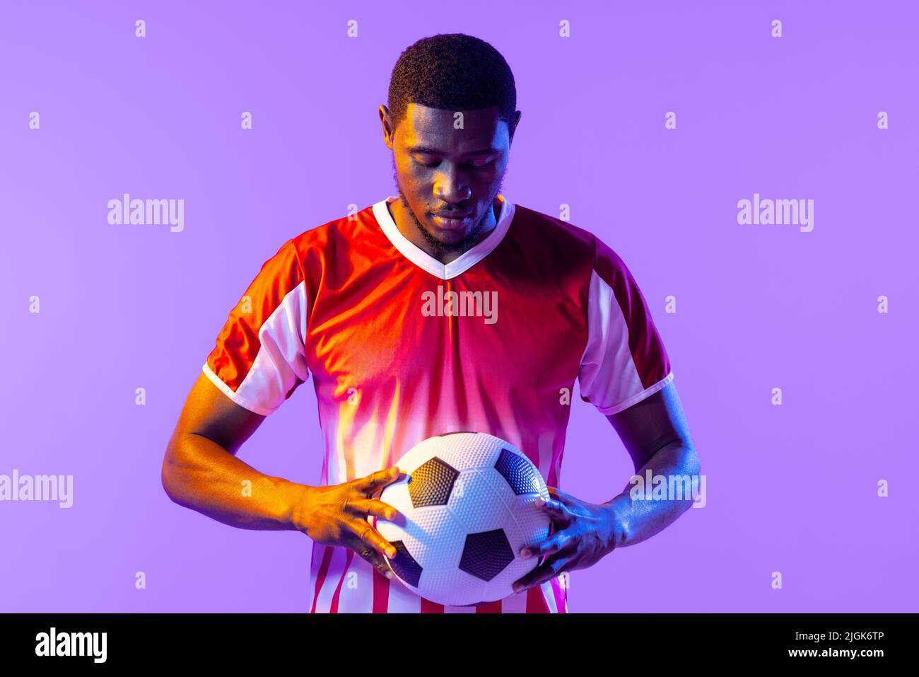 African american male soccer player with football over neon pink ...