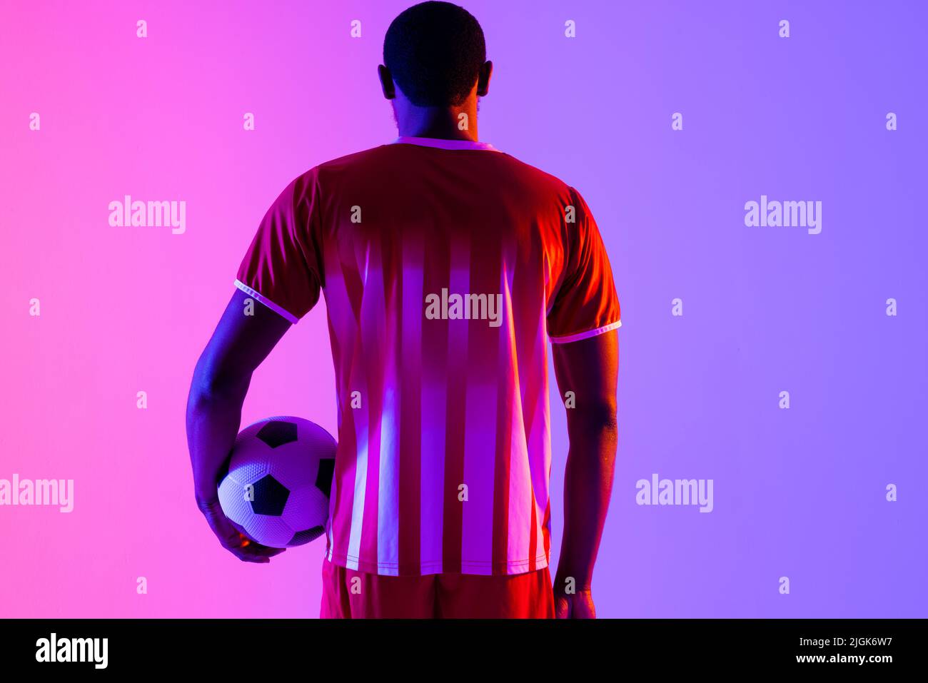 African american male soccer player with football over neon pink ...