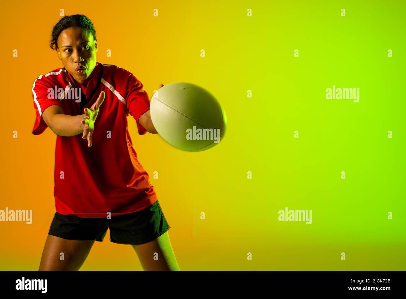 African american female rugby player with rugby ball over neon green ...