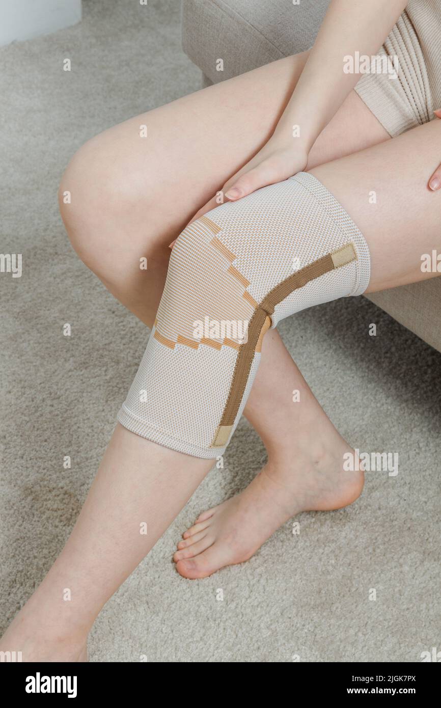 Knee support brace on a woman leg. girl in an orthosis in the interior ...