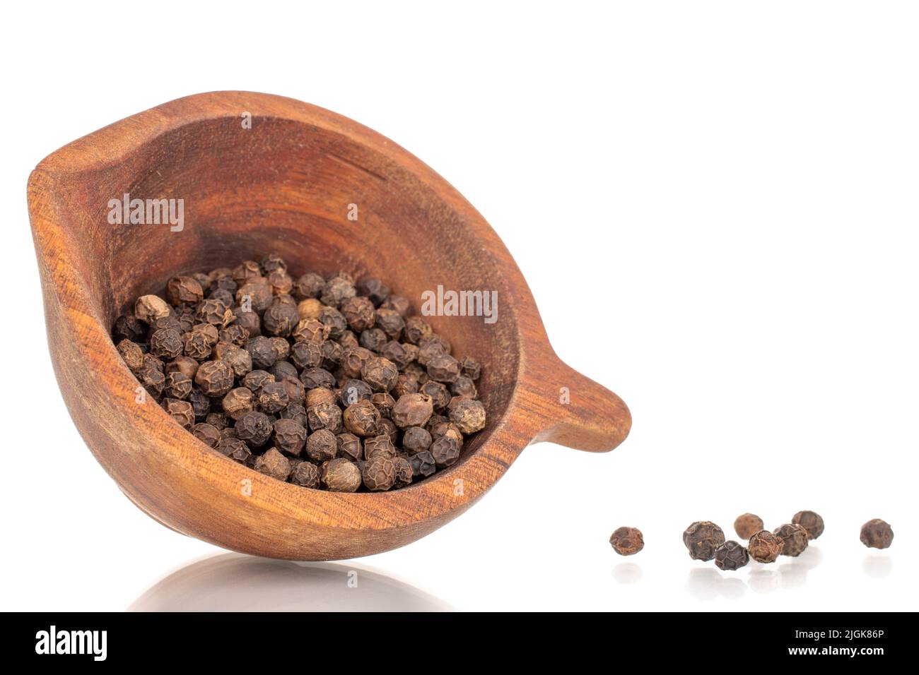 Dry fragrant black pepper in a wooden cup, close-up, isolated on a ...