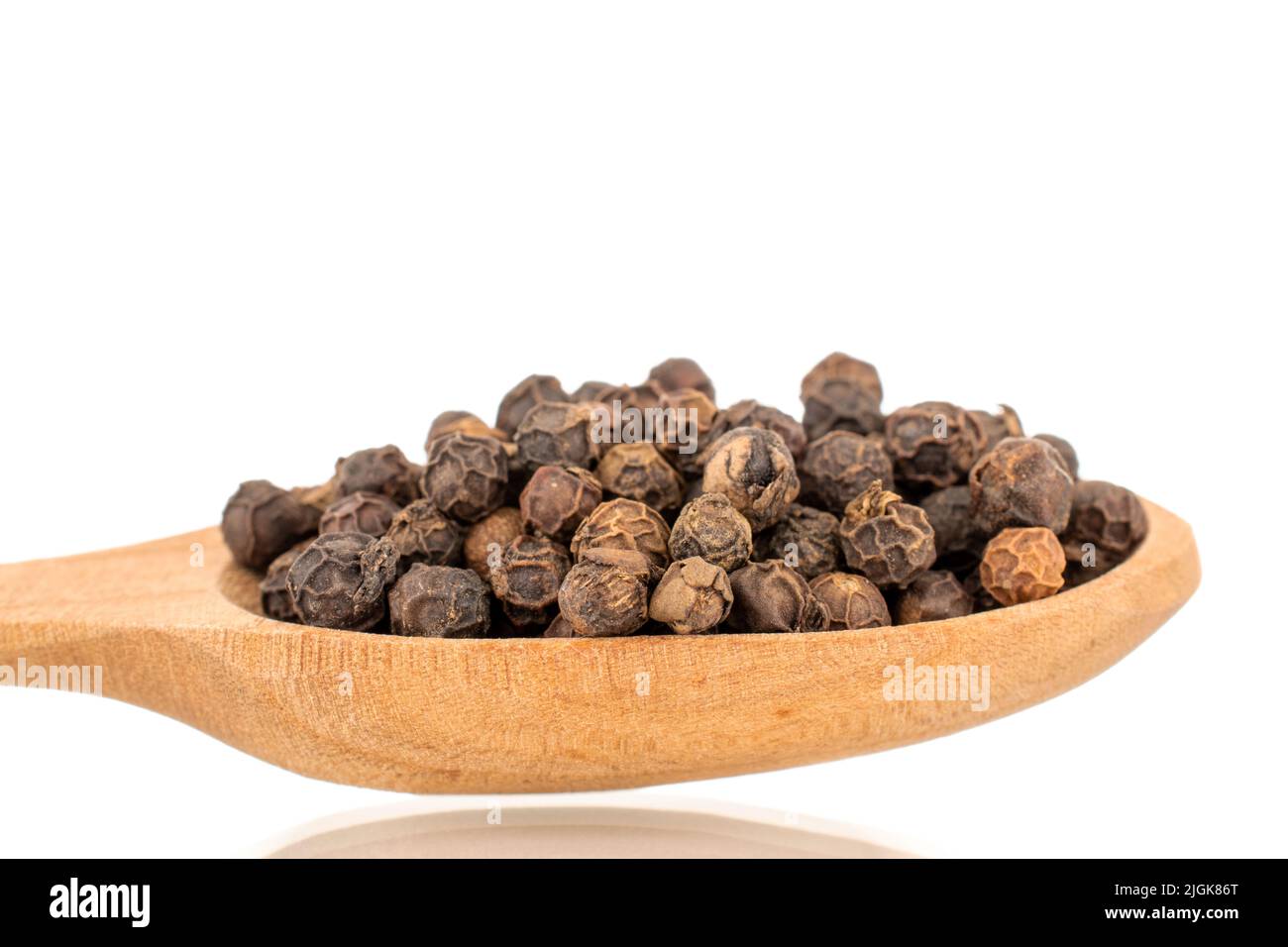 Dry fragrant black pepper in a wooden spoon, close-up, isolated on a ...