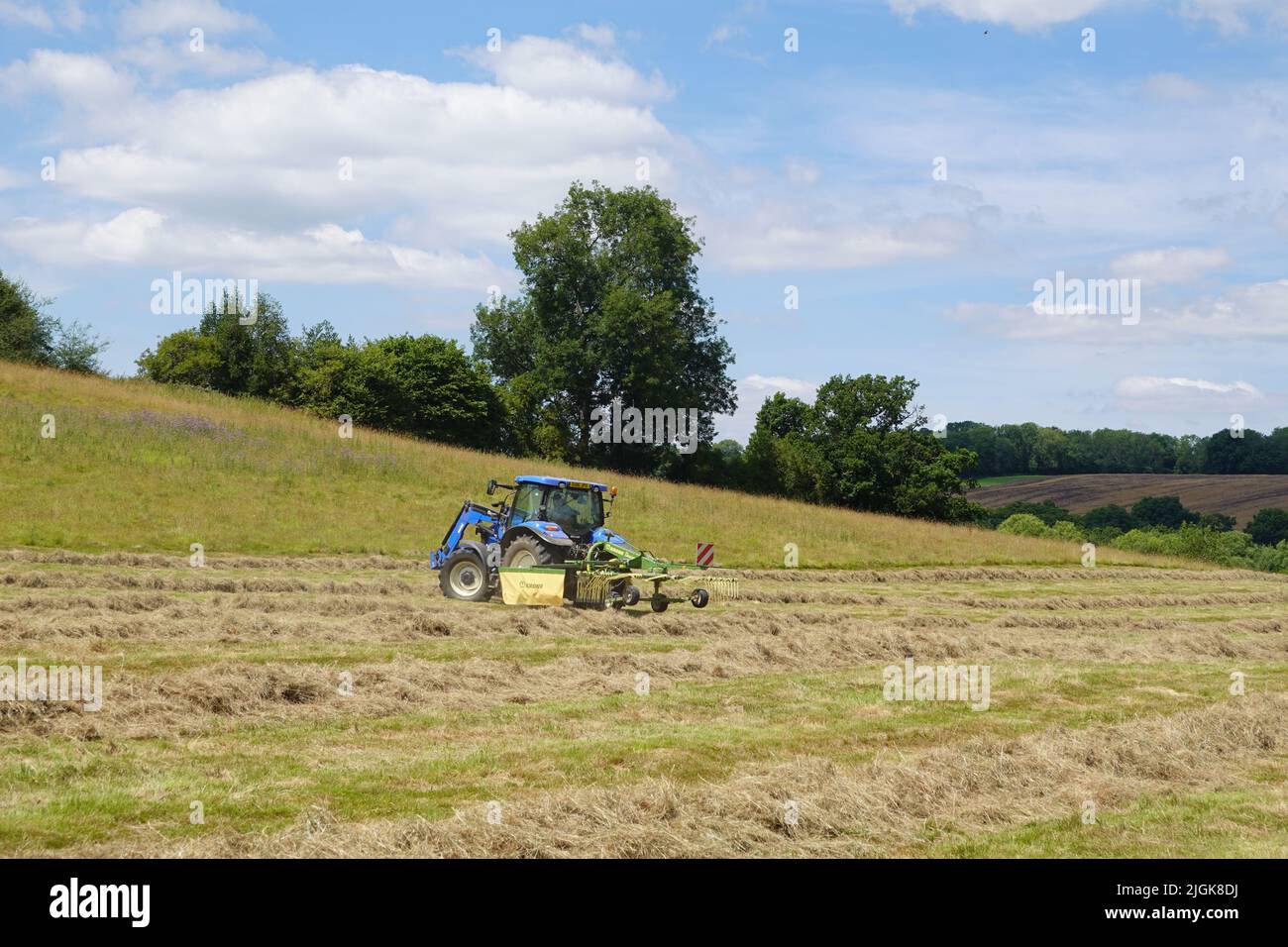 Farmer preparing straw for bailing near Hartfield East Sussex, England ...