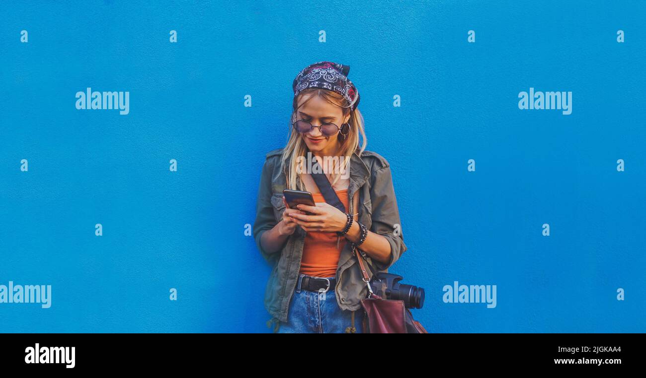 Young girl standing by the blue background holding a smartphone - A ...
