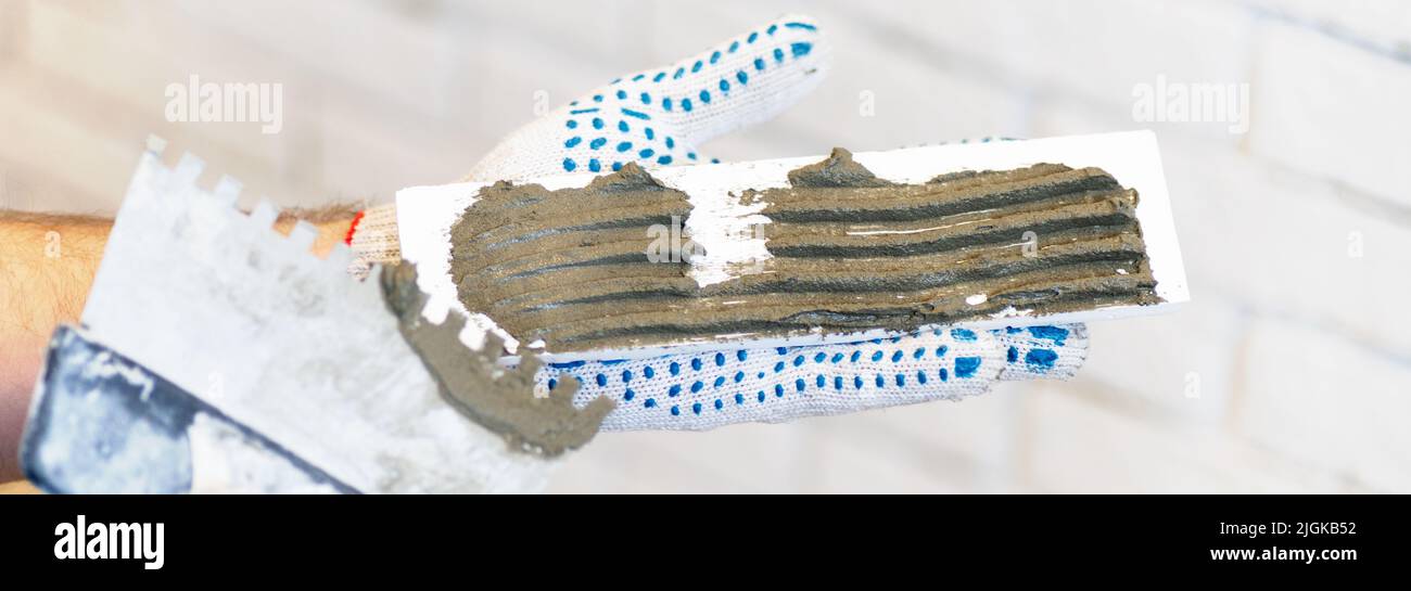 A professional builder sticks decorative tiles on the wall. A worker ...