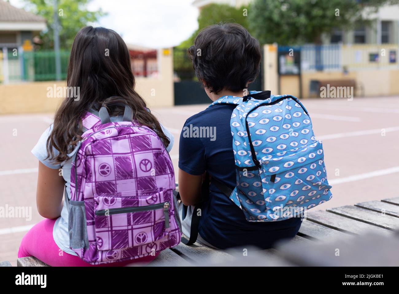 Rear view of two young children students with their backpacks. First ...