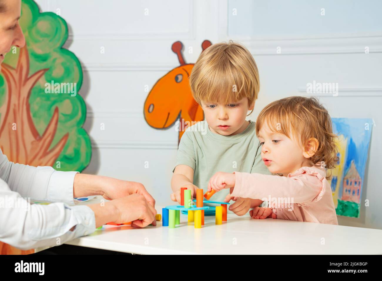 Woman and two little kindergarten kids build tower Stock Photo - Alamy