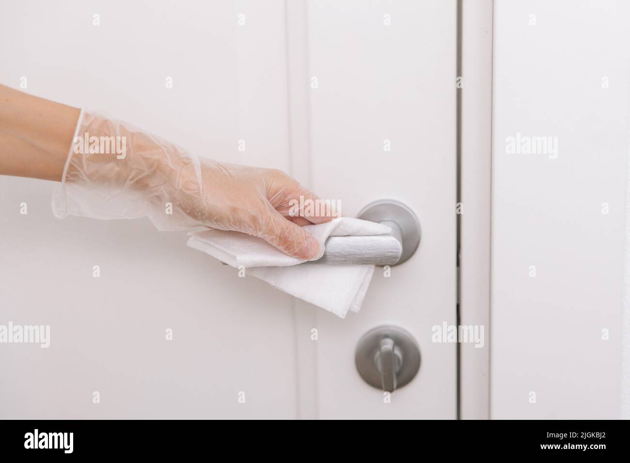 Cleaning door handles with wet wipe and white gloves. Woman hand using ...