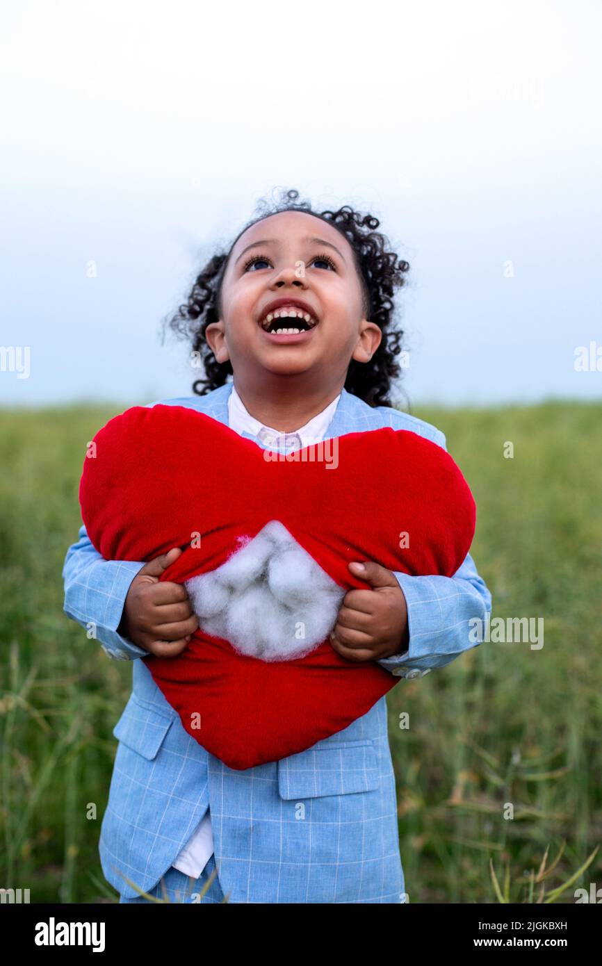 happy black boy in a suit standing outdoors and holding a ripped heart ...