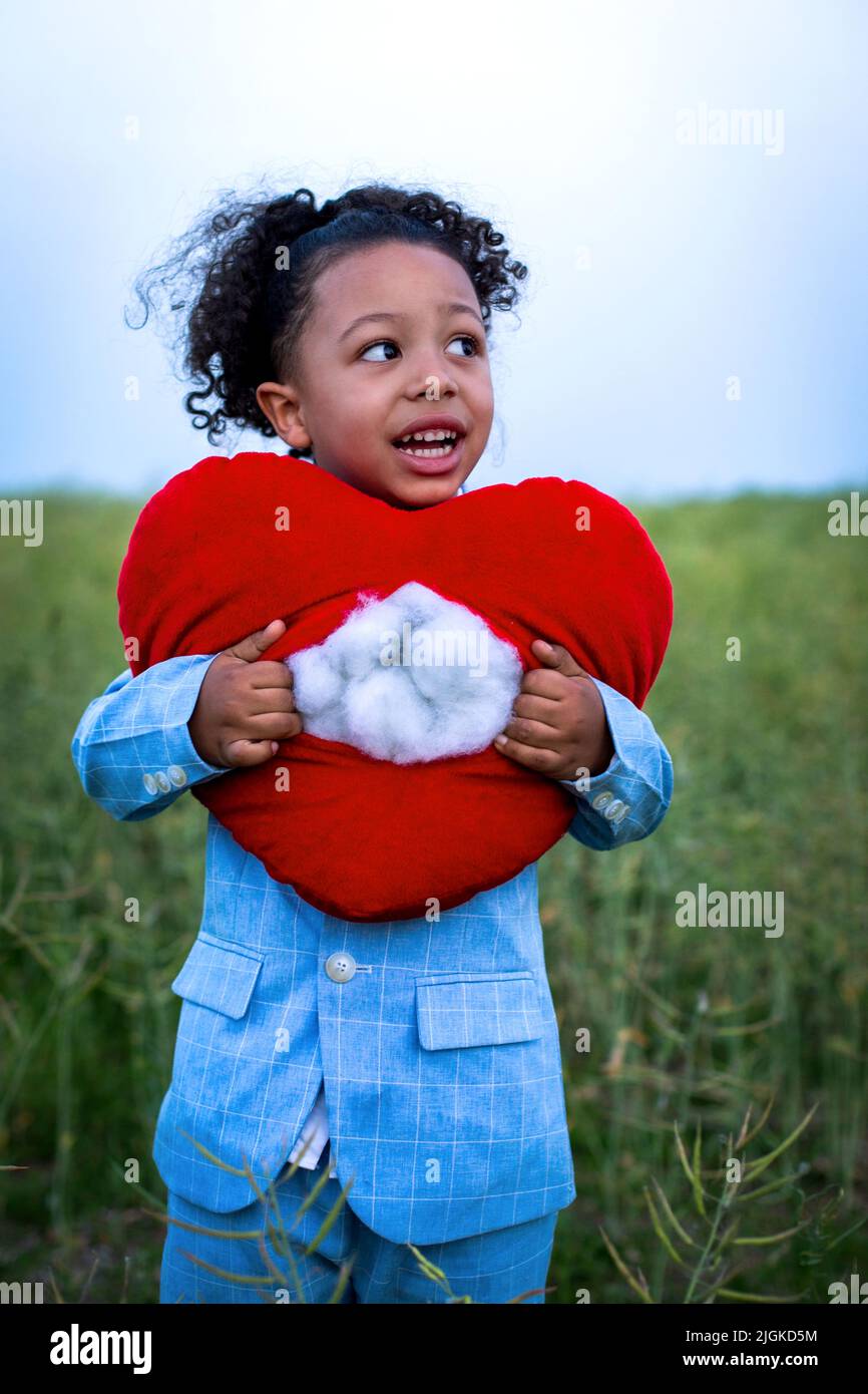 happy black boy in a suit standing outdoors and holding a ripped heart ...