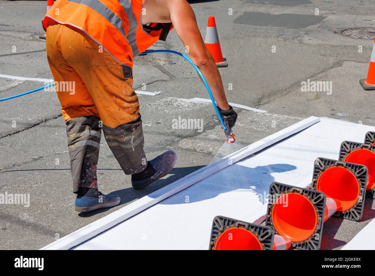 A road worker on a fenced section of the carriageway using a paint ...