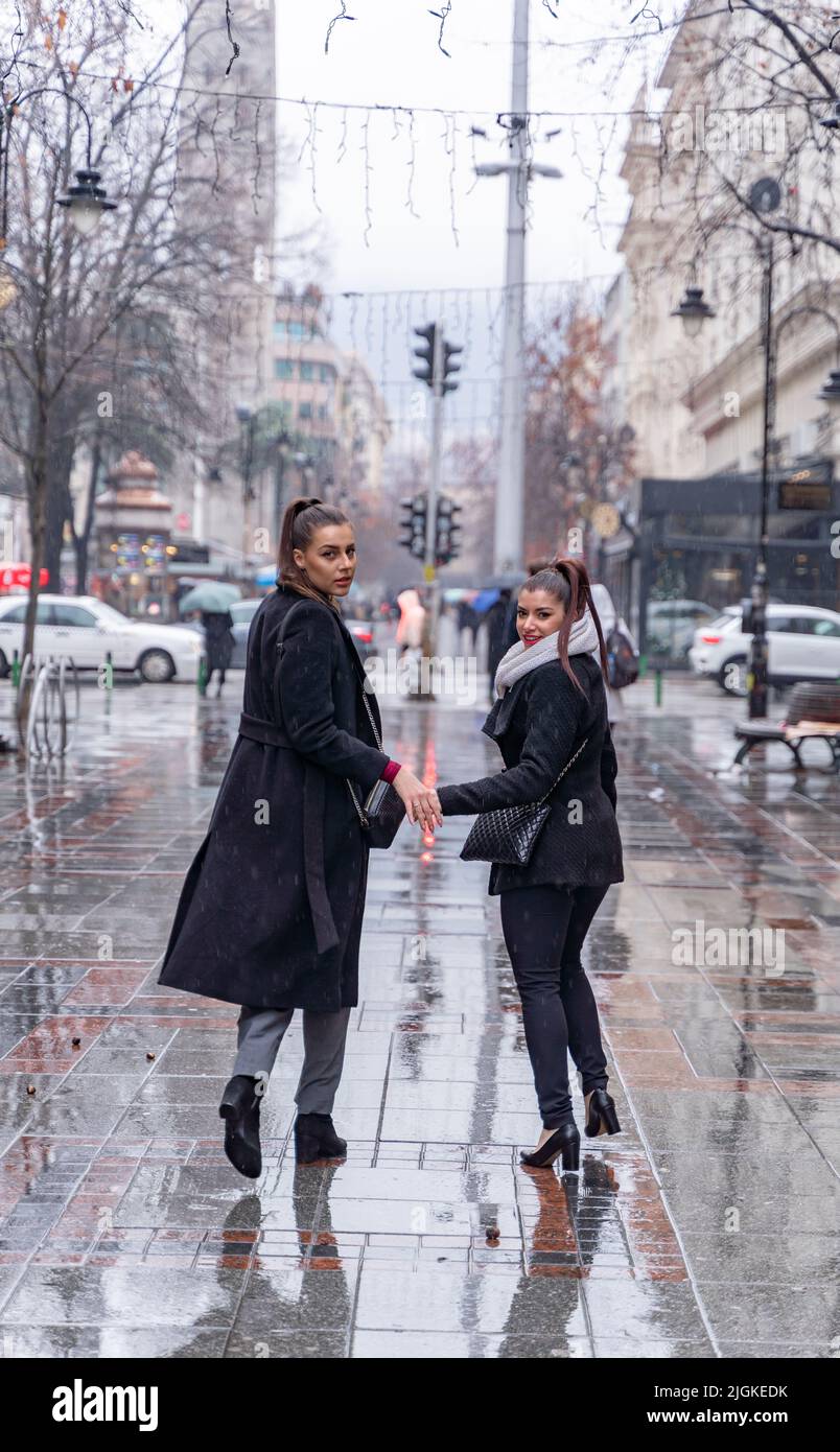 Two attractive and beautiful women are walking together on the rain ...
