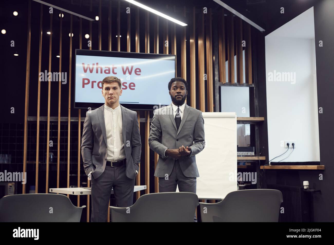 Portrait of serious successful young multi-ethnic men in suits standing ...