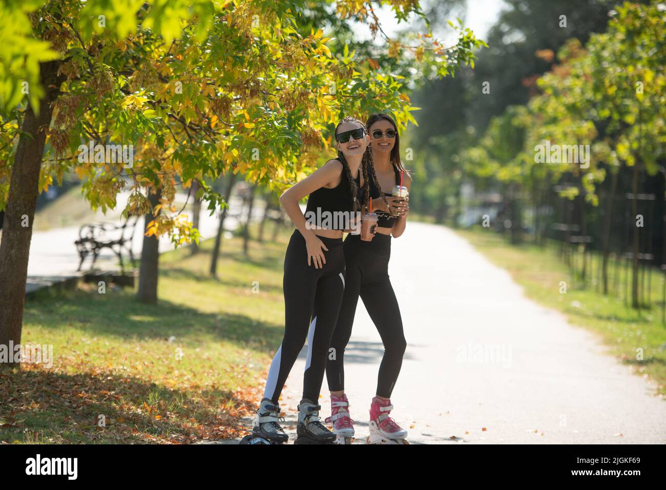 Two attractive best friends talking and drinking smoothies in the park ...