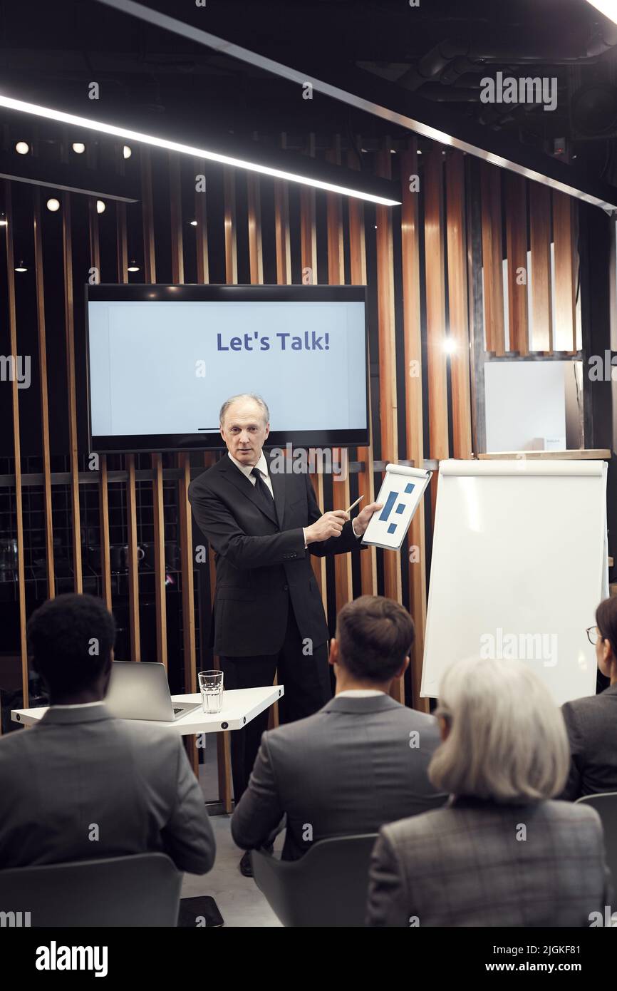 Experienced senior businessman in suit standing against plasma screen ...