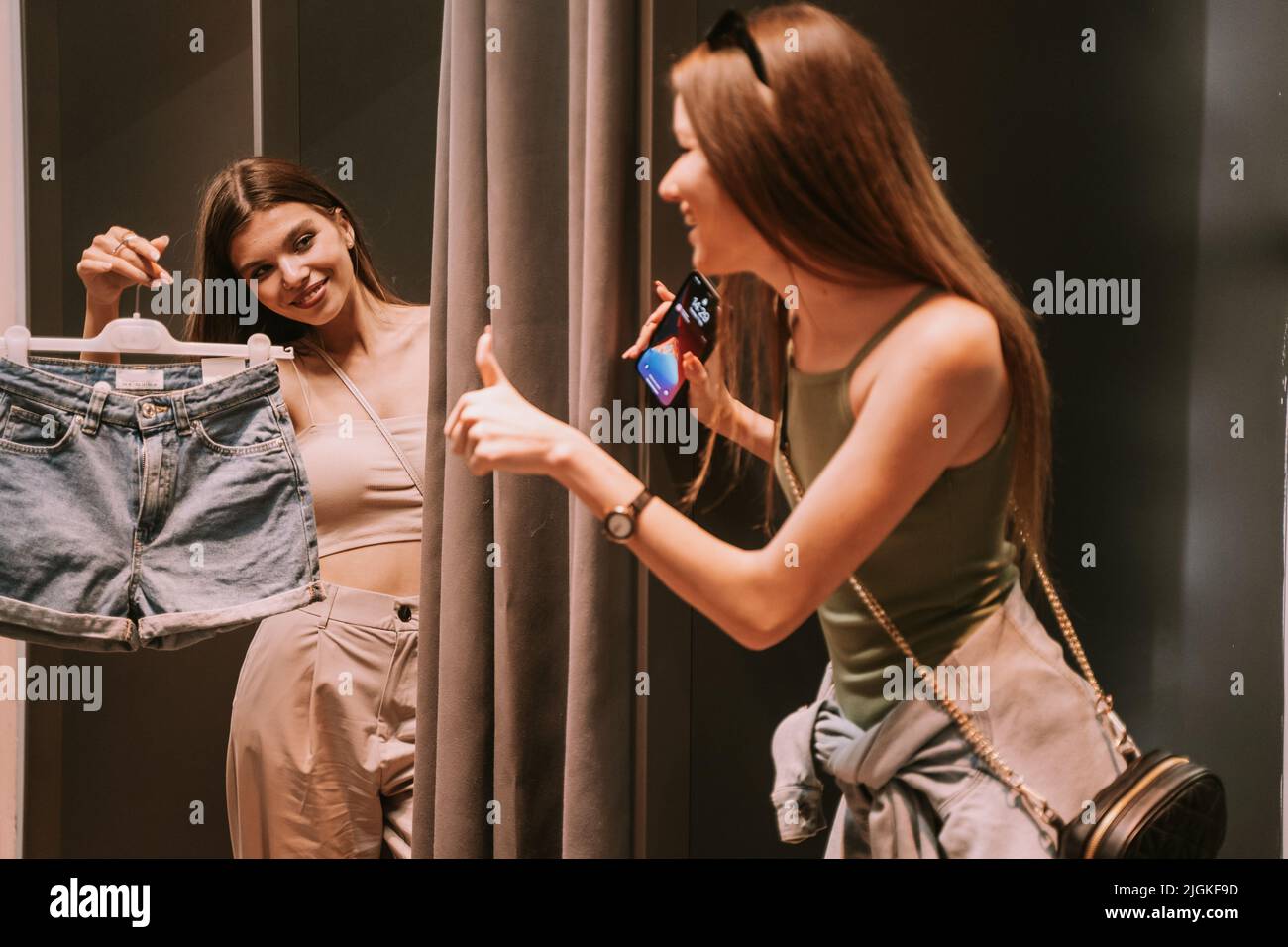 Two pretty best friends standing in the changeing room. One of the ...