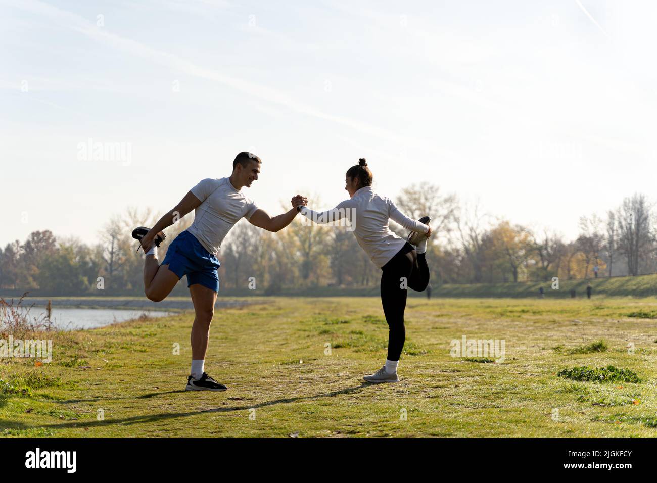 Two amazing and fit friends are balancing on one leg while holding each ...