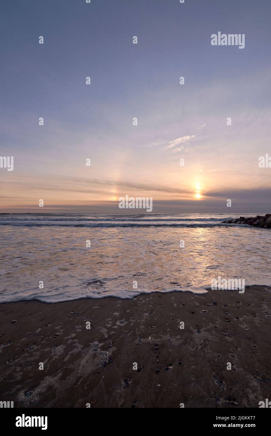 Sunrise from the beach with a breakwater. Rainbow, Circle around the ...