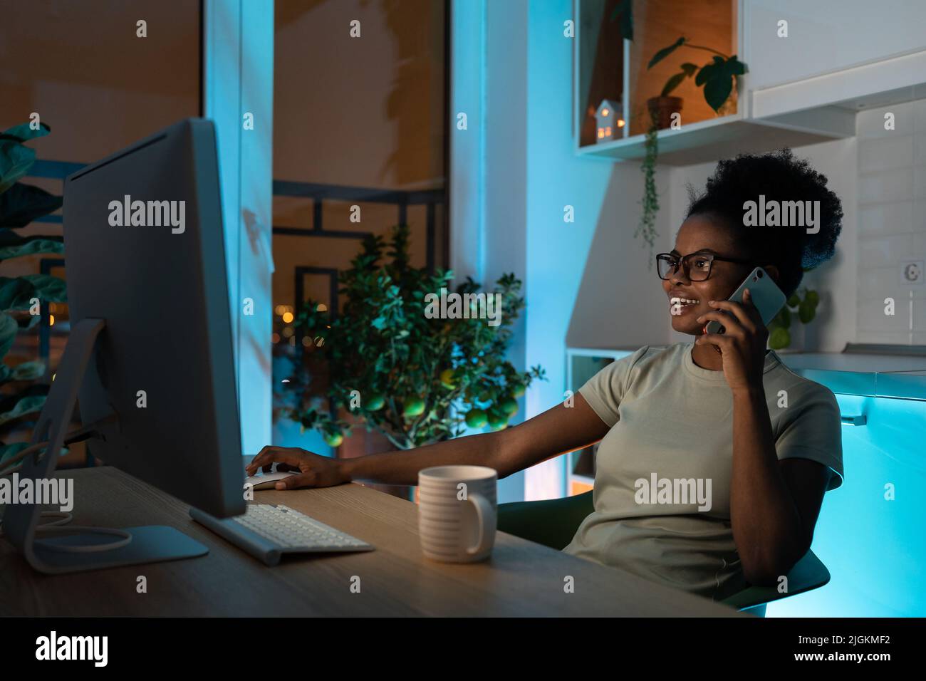 Positive black woman in glasses talking on smartphone, working on ...