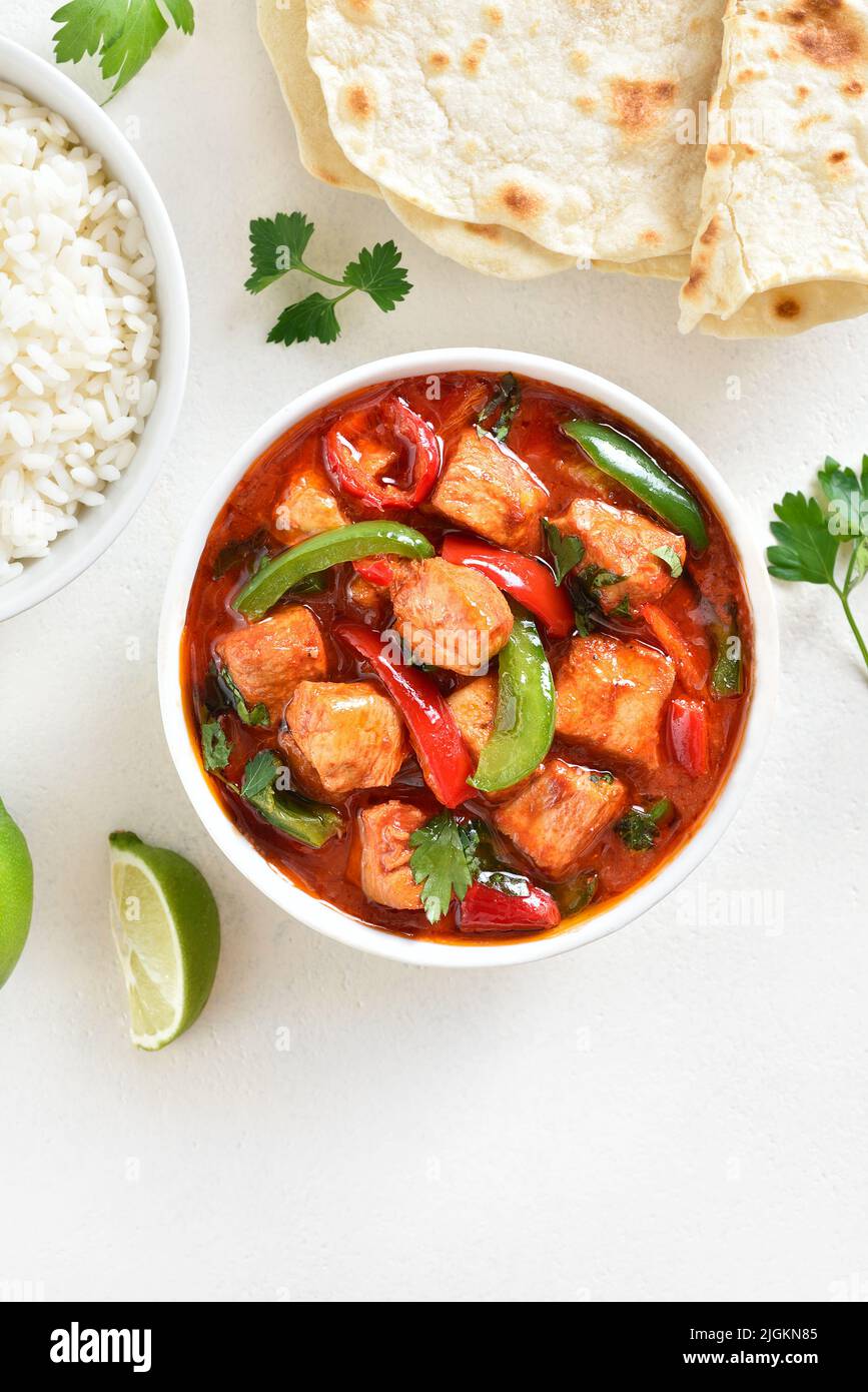 Thai style red chicken curry with vegetables in bowl over light ...