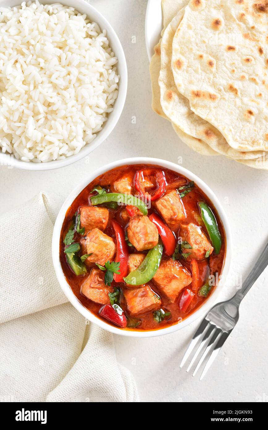 Thai style red chicken curry with vegetables in bowl over light ...