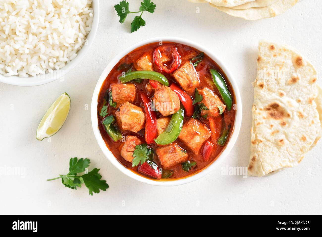 Thai style red chicken curry with vegetables in bowl over light ...