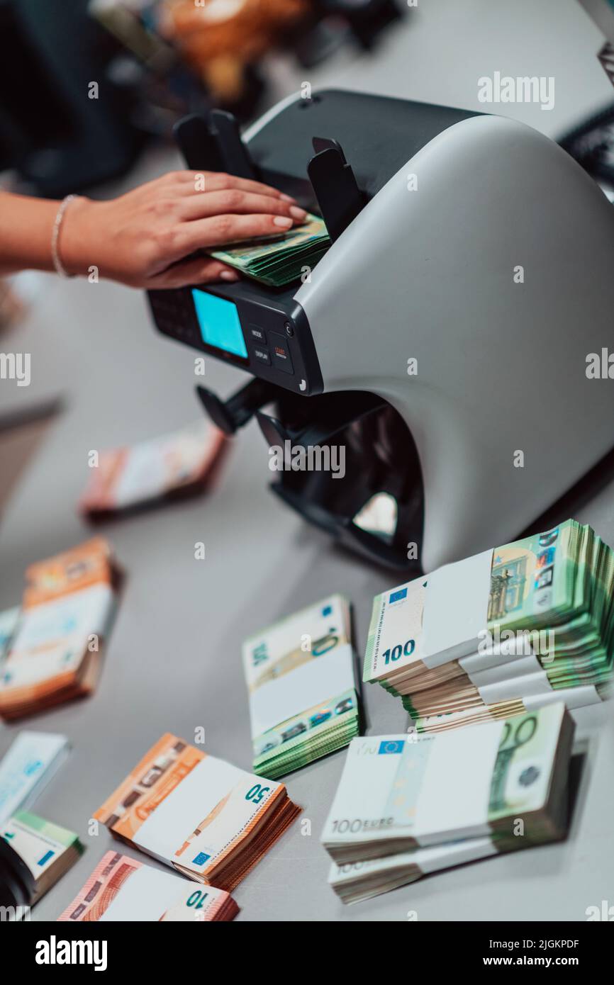 Bank employees using money counting machine while sorting and counting ...