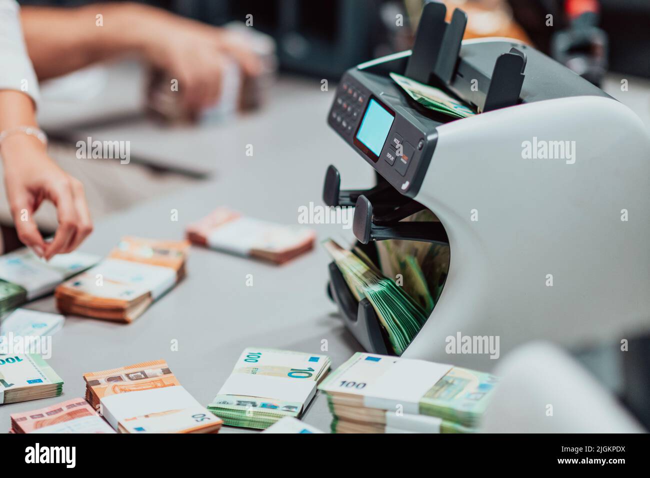 Bank employees using money counting machine while sorting and counting ...
