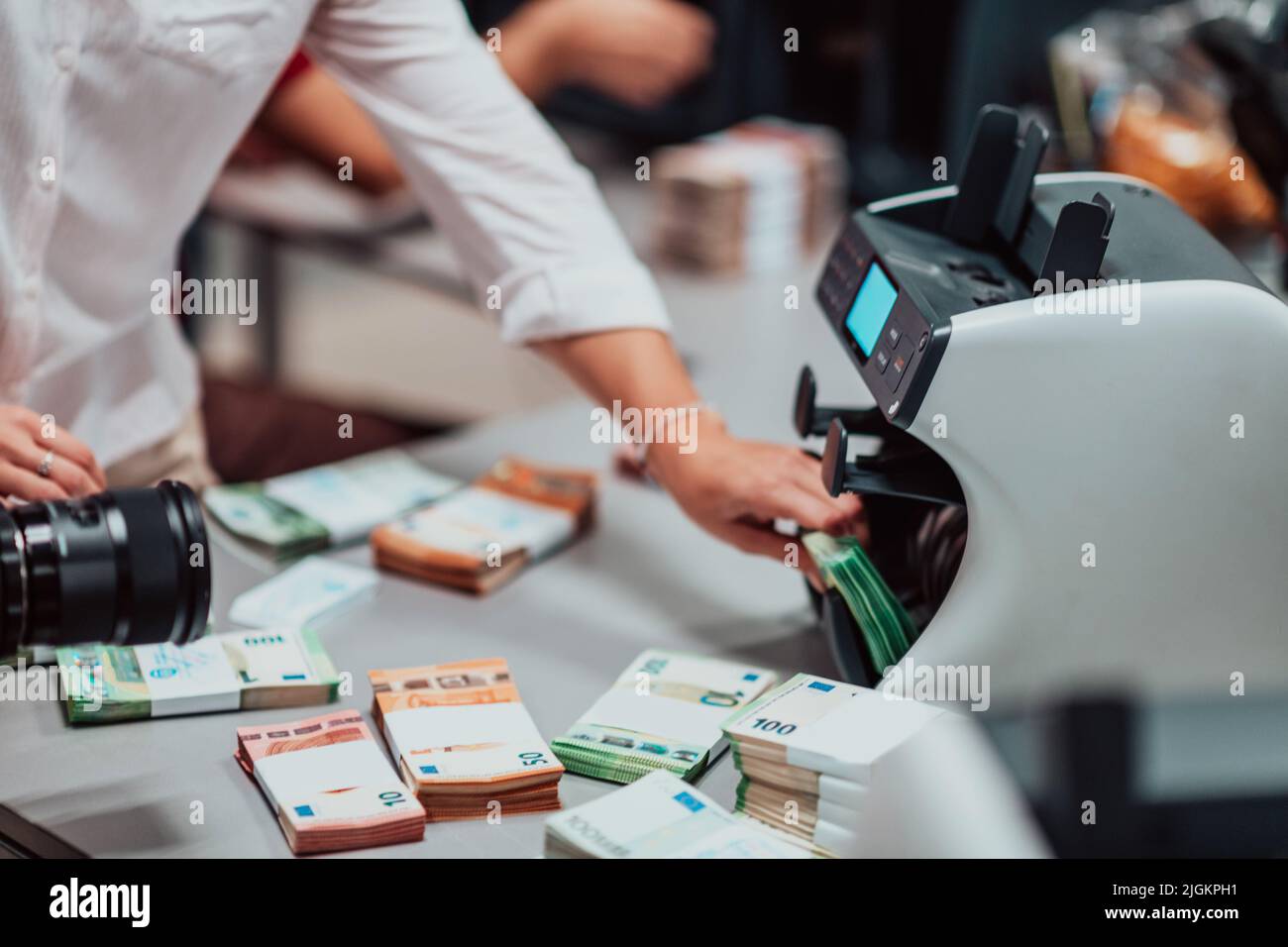 Bank employees using money counting machine while sorting and counting ...